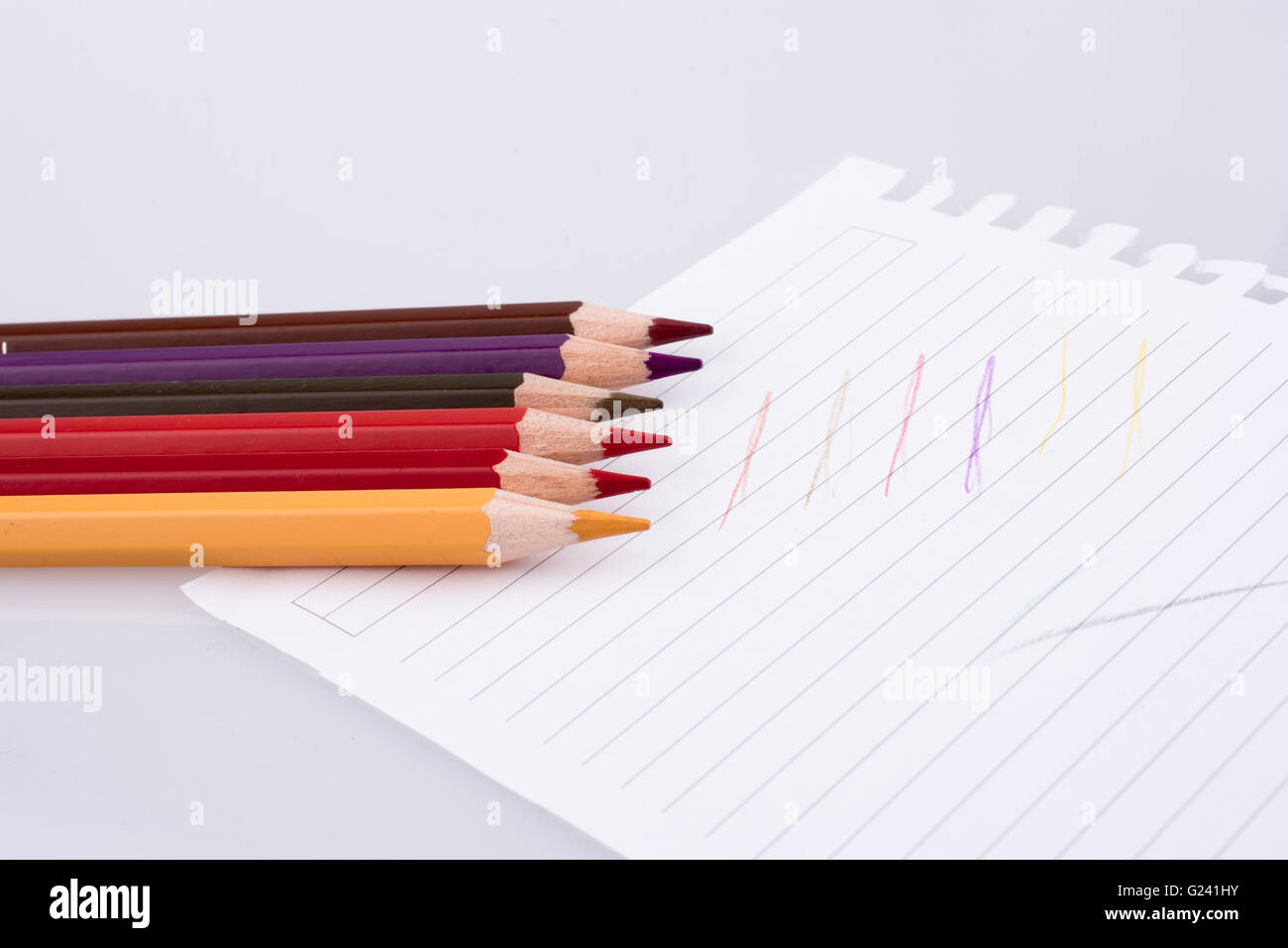 color pencils of various colors on a sheet of paper on a white ...