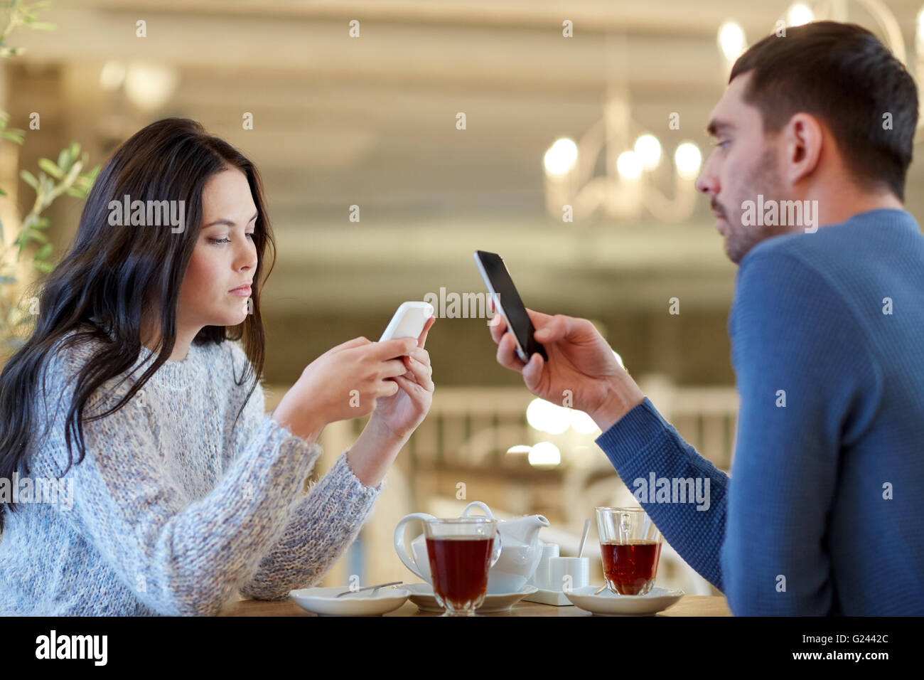 couple with smartphones drinking tea at cafe Stock Photo - Alamy
