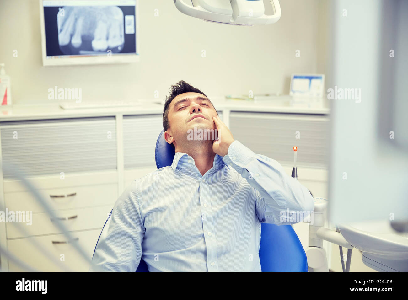 man having toothache and sitting on dental chair Stock Photo - Alamy
