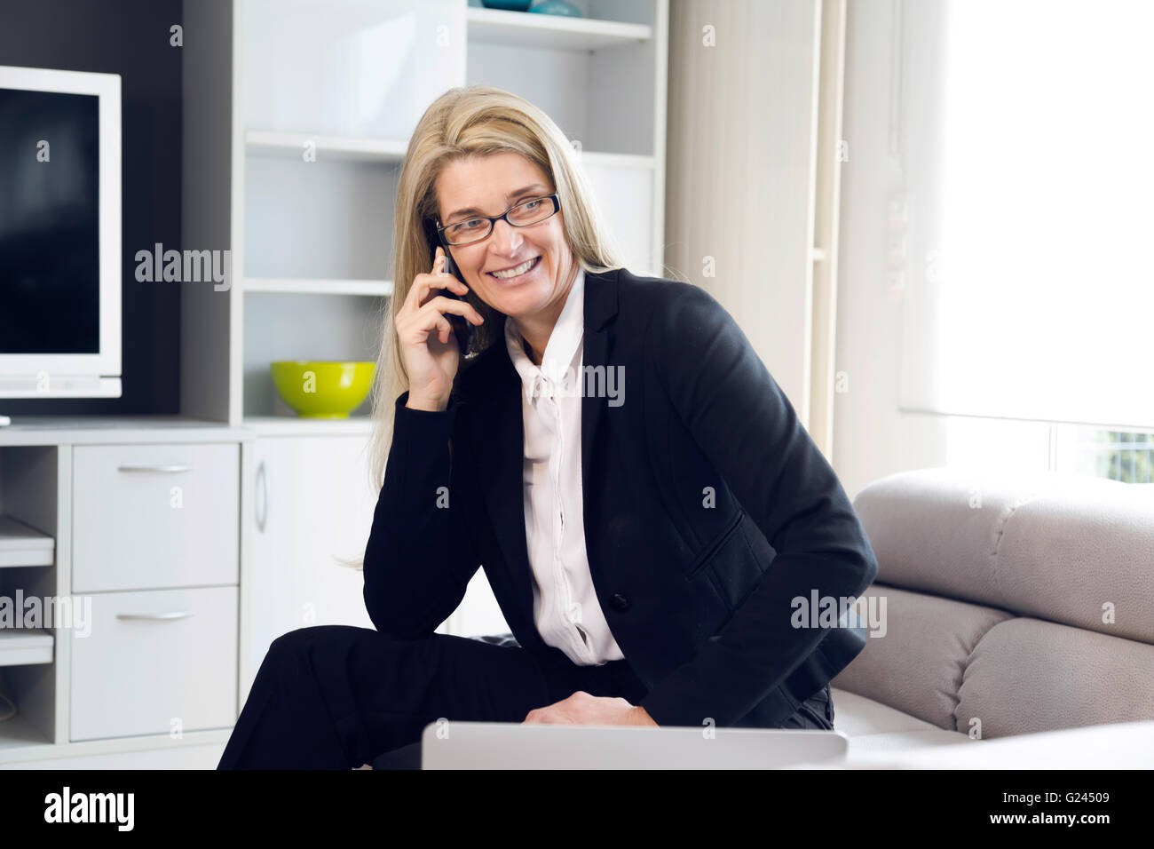 A business woman making a phone call from home. Light colored modern ...