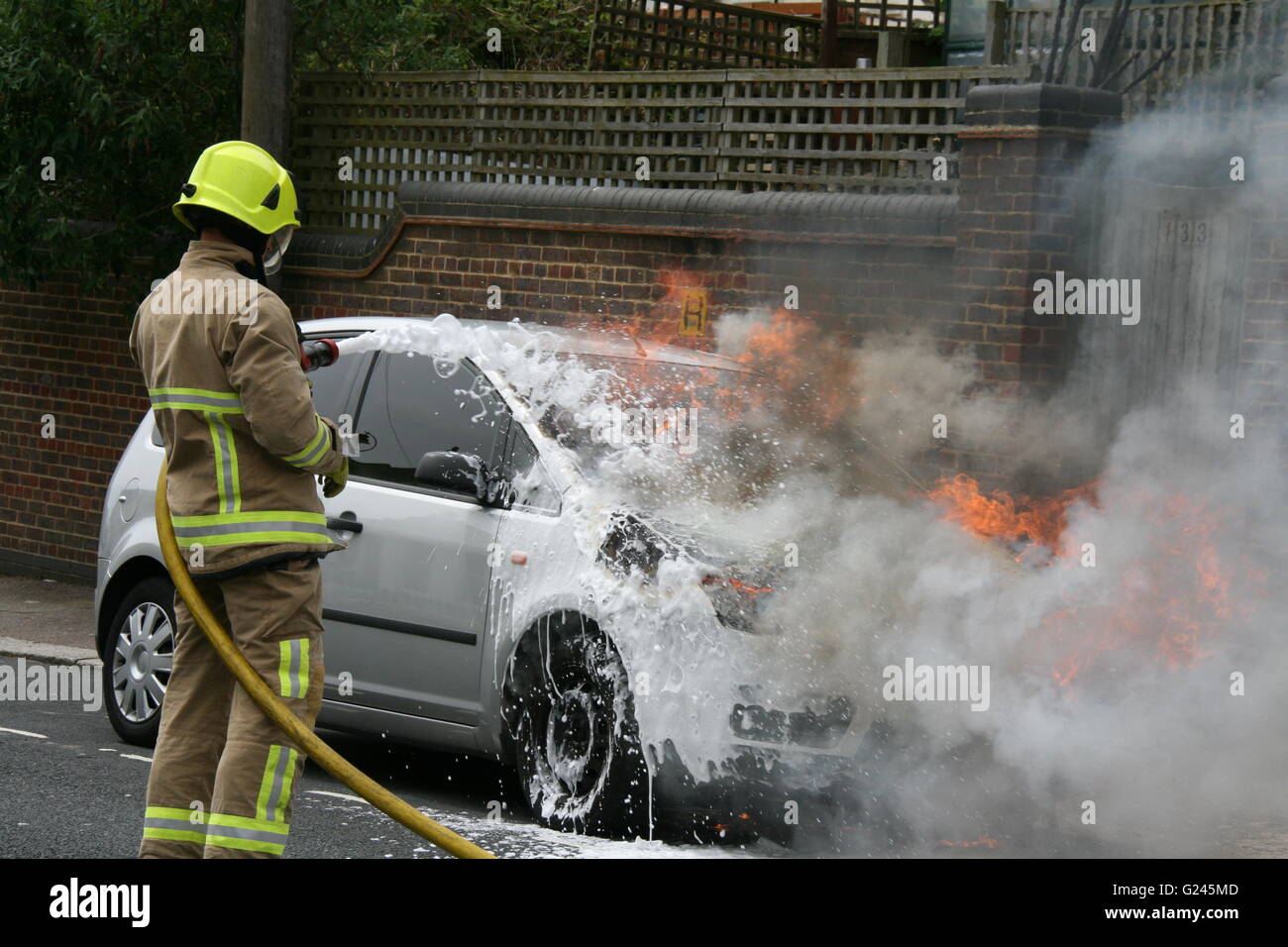 FIREFIGHTER TACKLING A CAR FIRE WITH HOSE Stock Photo - Alamy