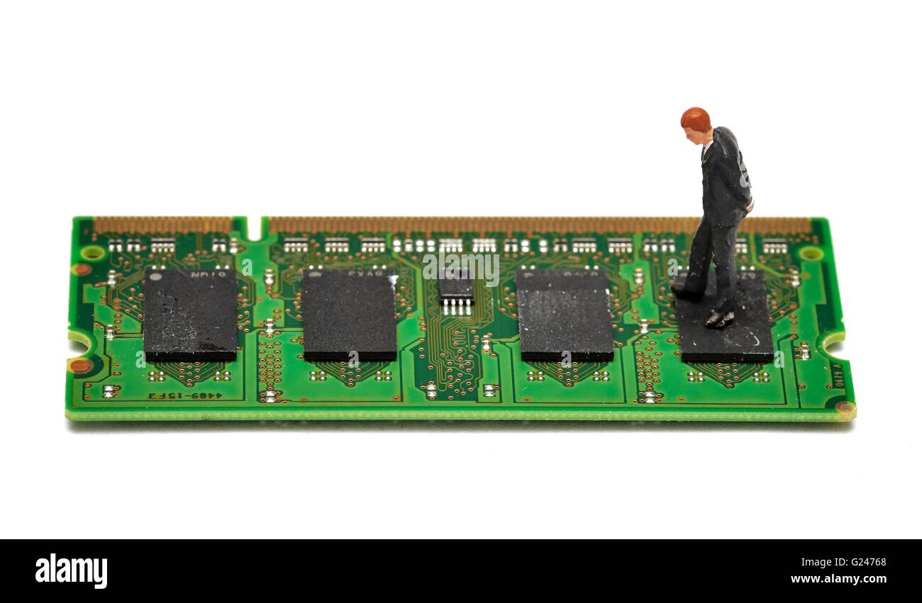 A miniature figurine businessman looking down on computer chip memory ...