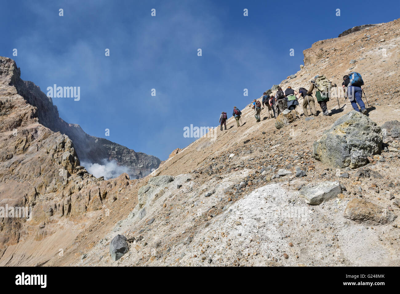 Group of tourists climbing on the steep slope to the active crater ...