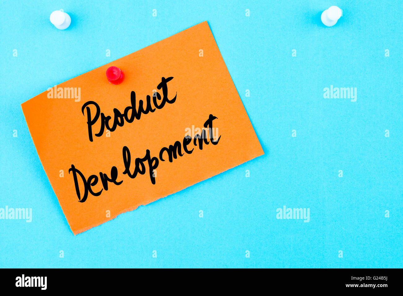 Product Development written on orange paper note pinned on cork board ...