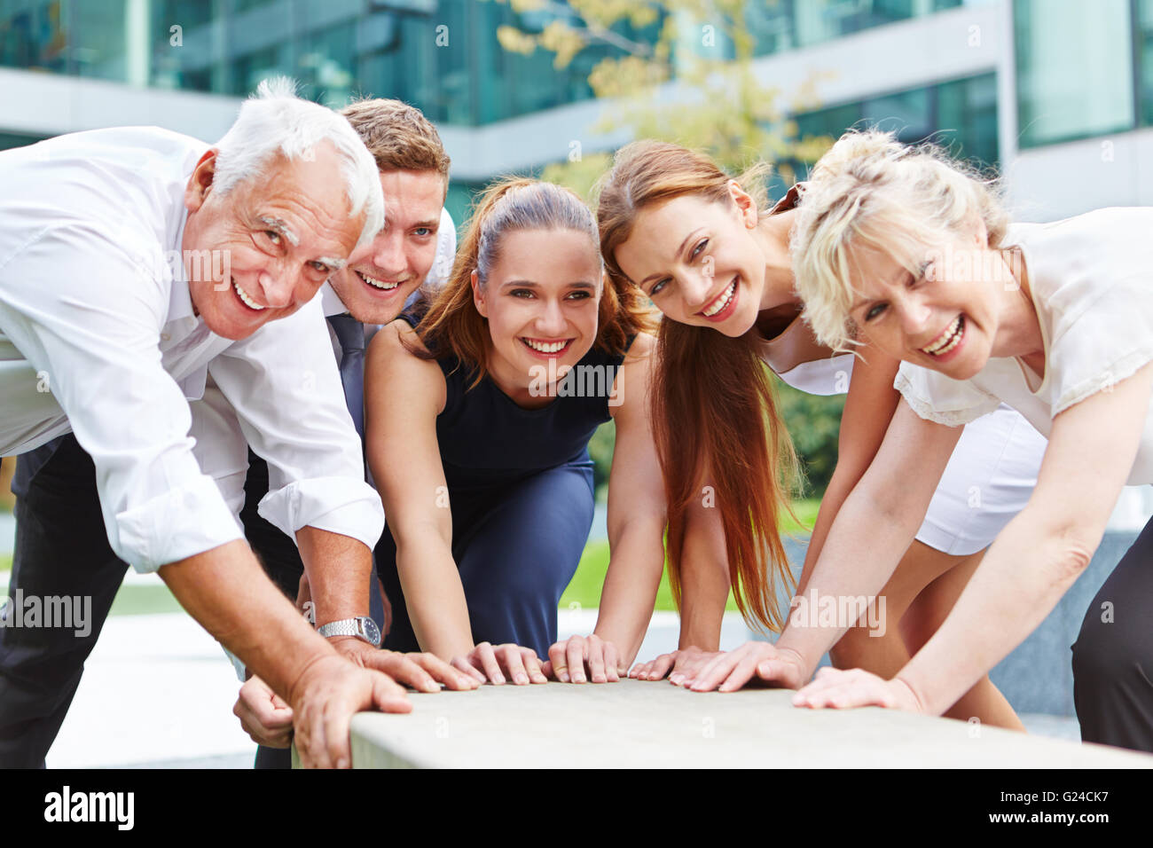 Happy business team working and pushing together for success outdoors ...