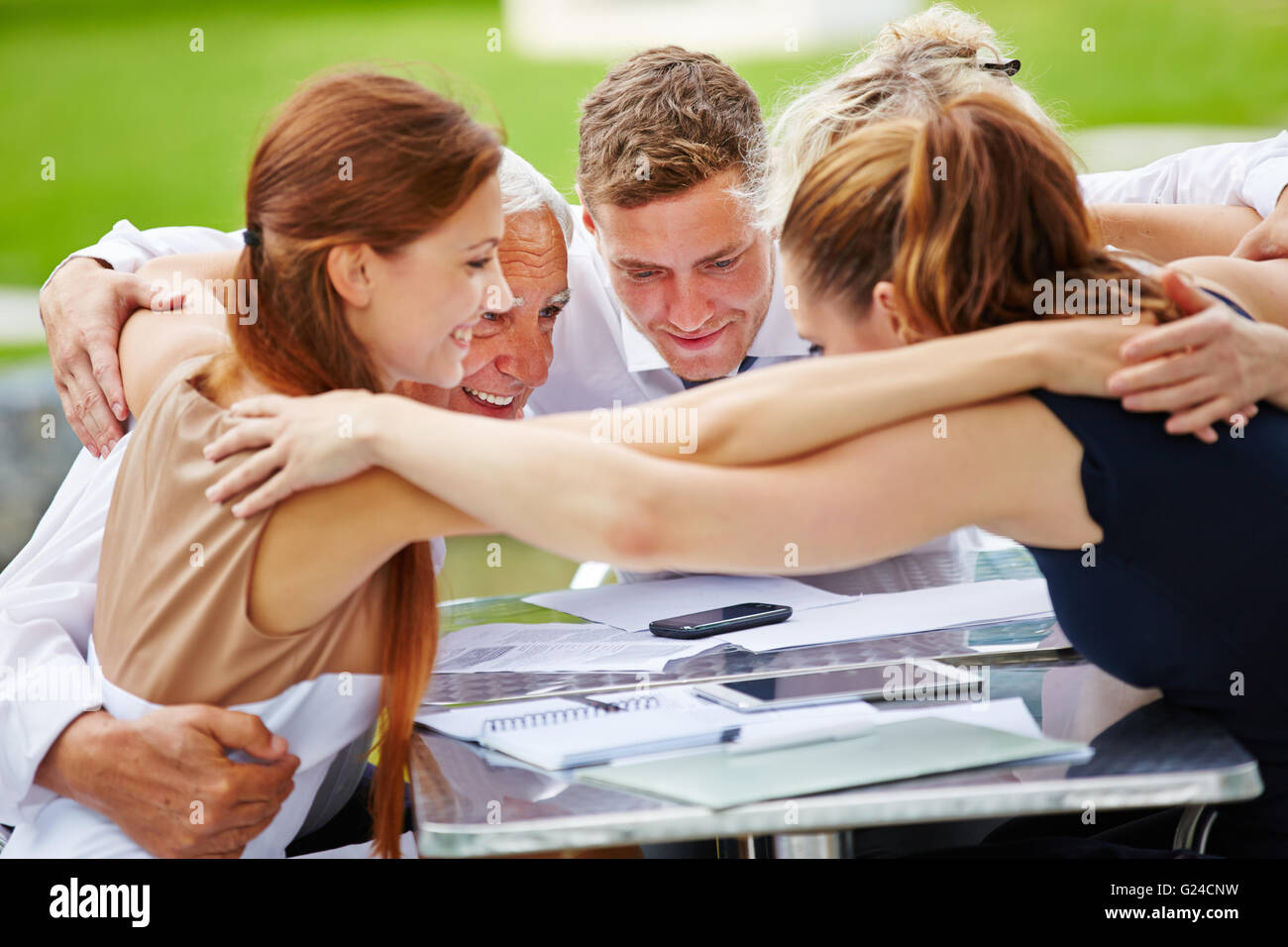 Business people hugging for team spirit in a meeting at a table Stock ...