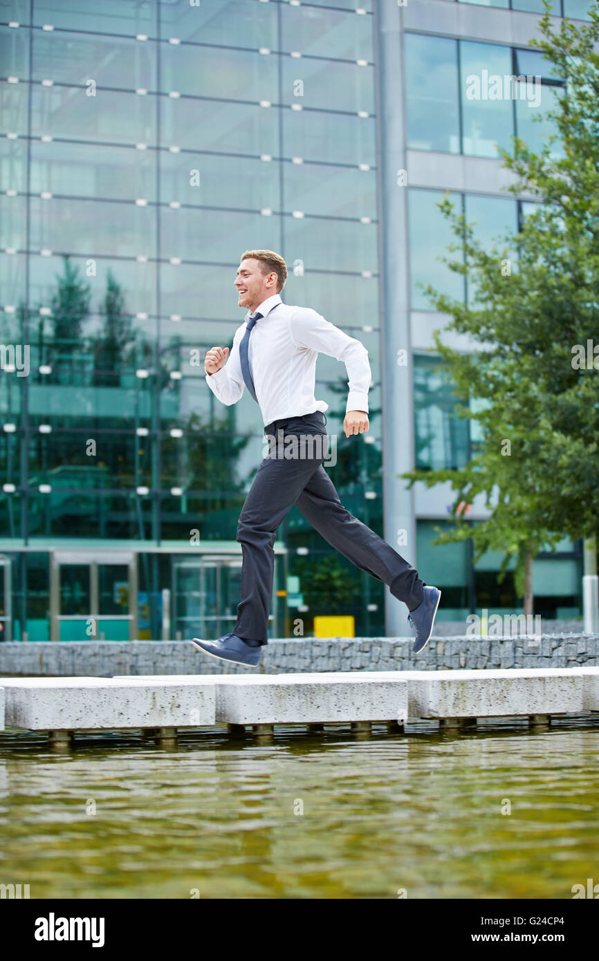 Smiling business man running to appointment in front of office building ...