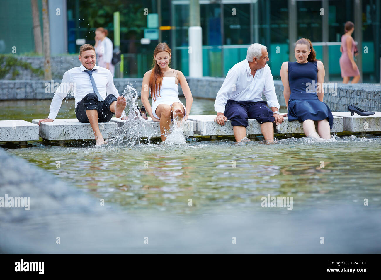 Funny happy business people splashing water with their feet in a lake ...