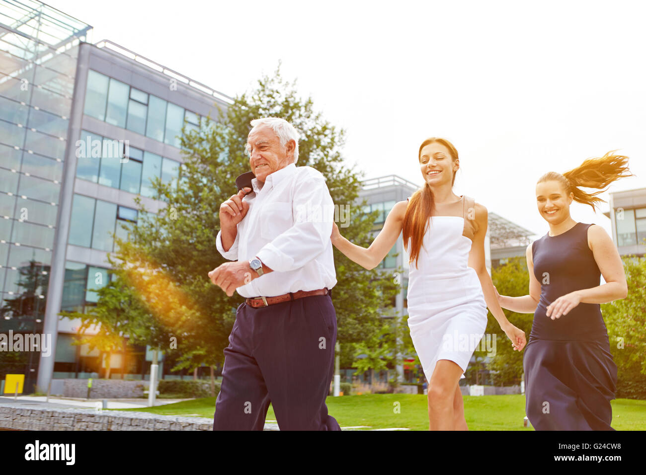 Senior manager and business women running behind each other outdoors ...