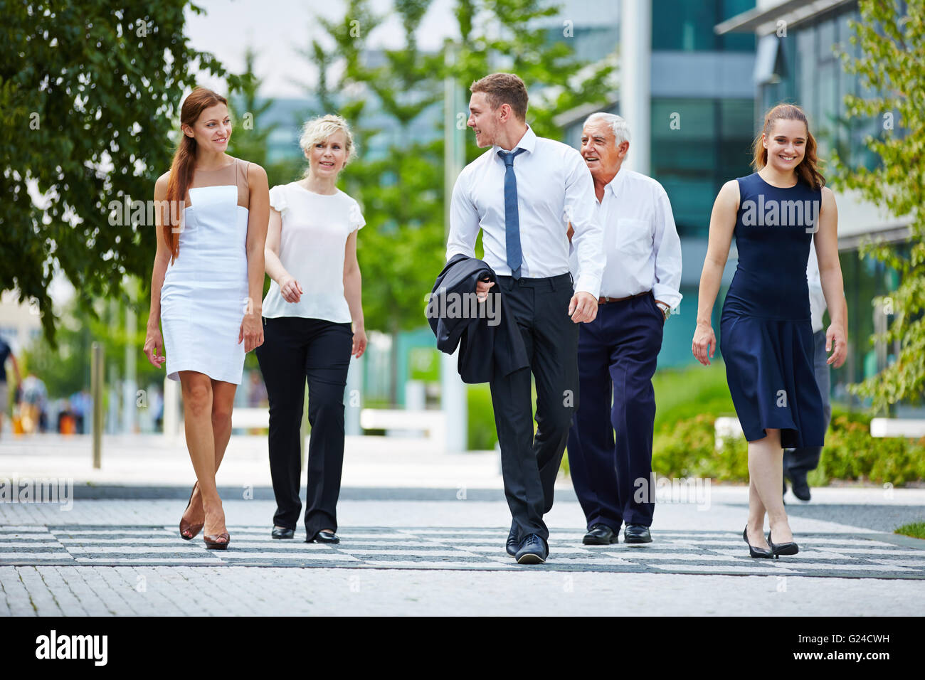 Group of business people walking and talking together outdoors in ...