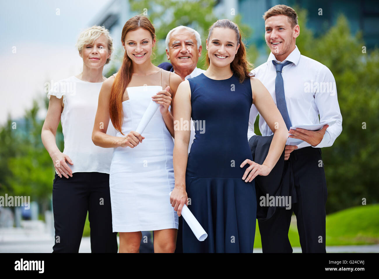 Happy business team with senior manager and smiling trainees outdoors ...