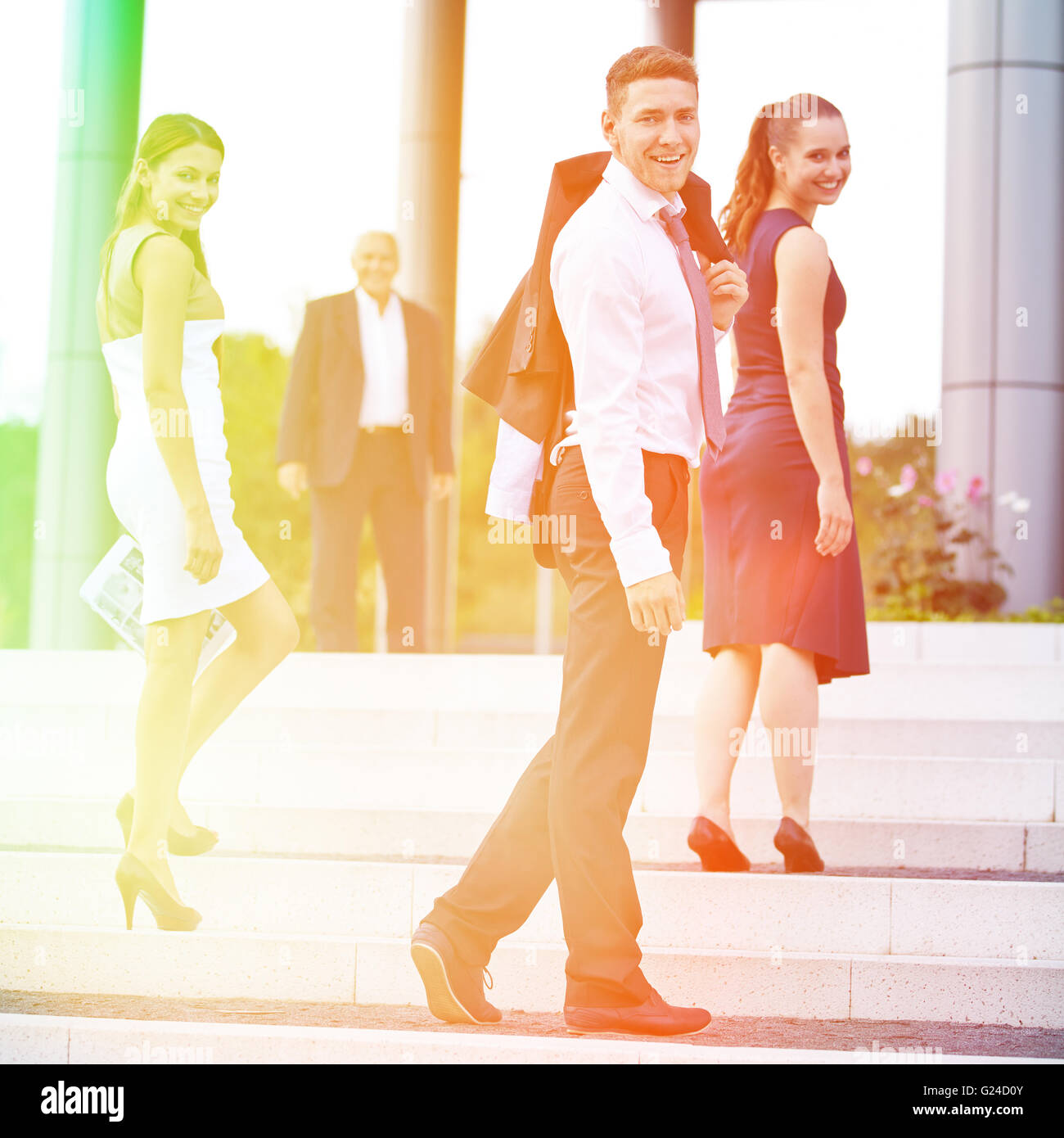 Young business people walking up stairs and turning around smiling ...