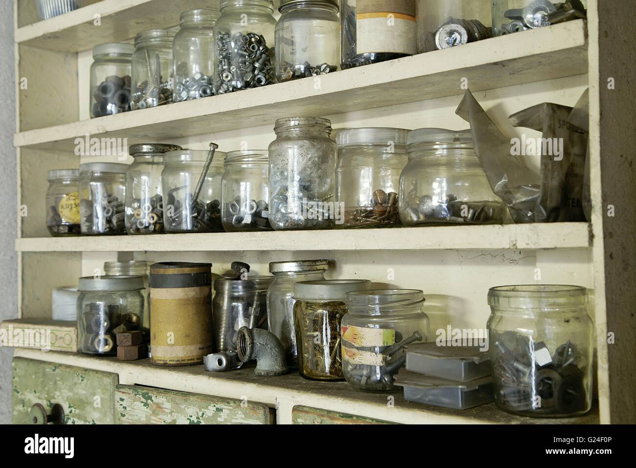 Various vintage old jars with metal bolts, nuts and screws on wooden ...