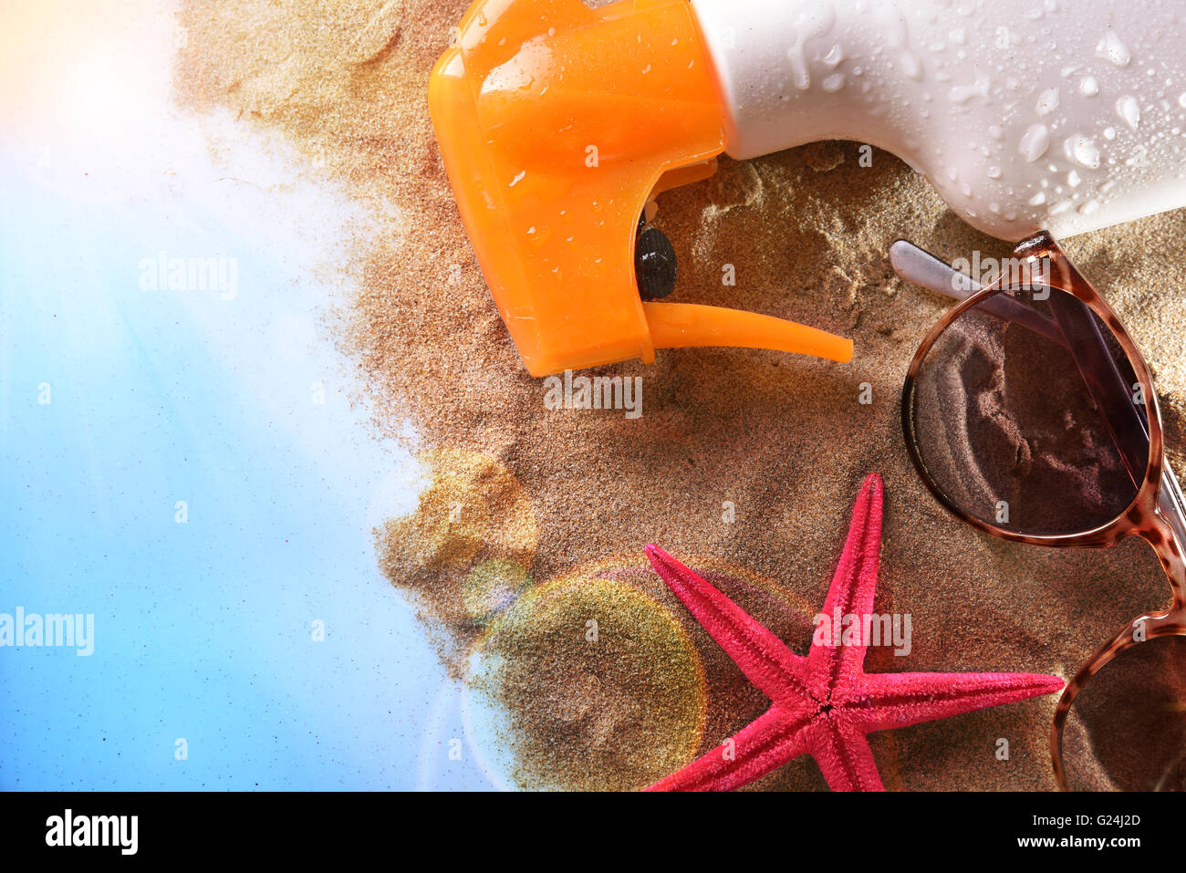 Sunscreen spray and sunglasses on sand in blue glass table with sun ...