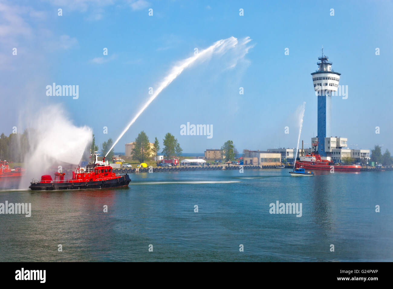 Fire fighting boat sprays water in port Stock Photo - Alamy