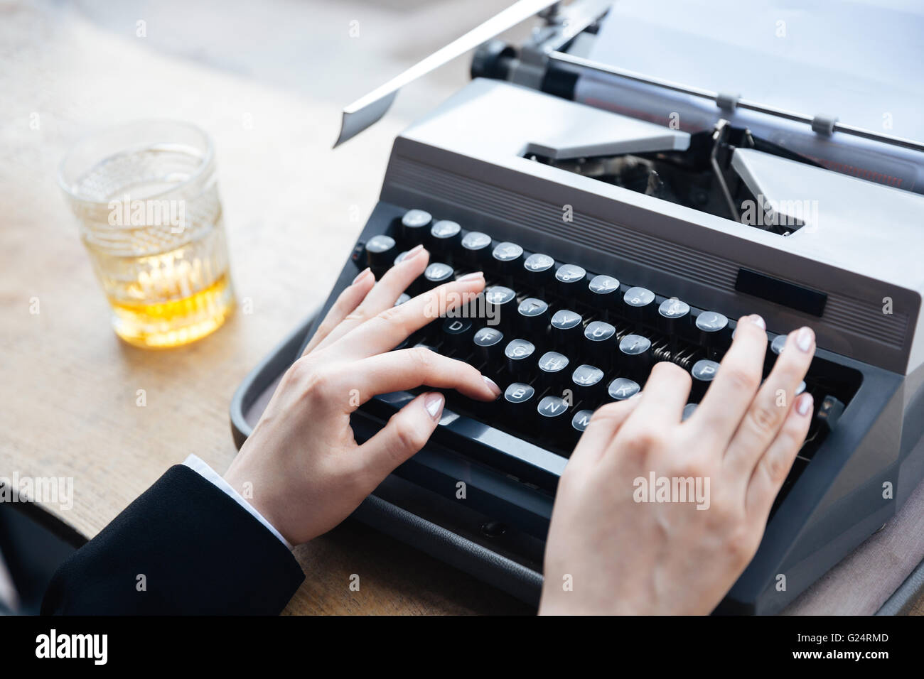 Woman's hands writing on old typewriter over wooden table background ...