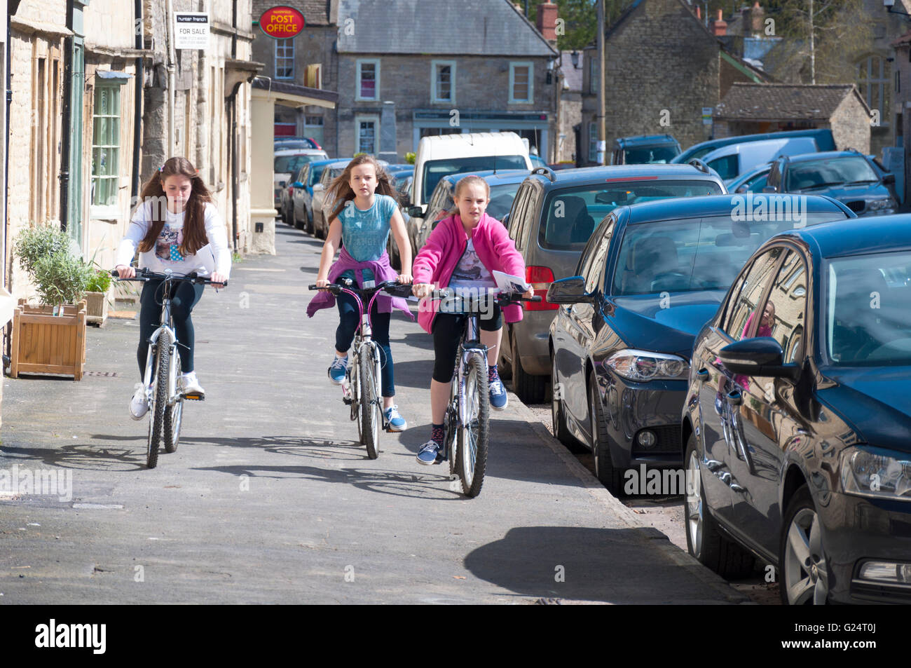 Children cycling on pavement in The High Street in Marshfield ...