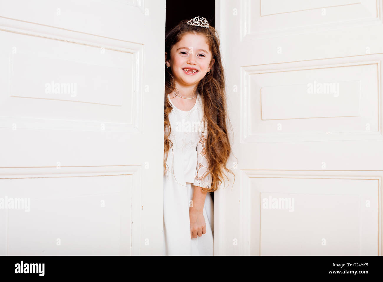 little cute girl at home, opening door well-dressed in white dress ...