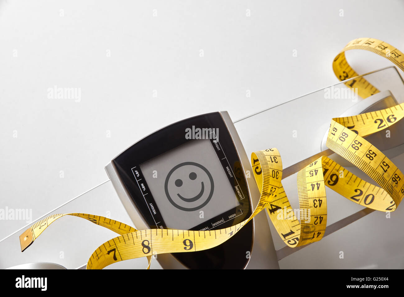 Scale with happy face message and measuring tape on white table. Weight ...