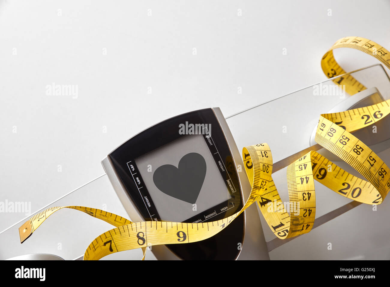 Scale with healty heart message and measuring tape on white table ...