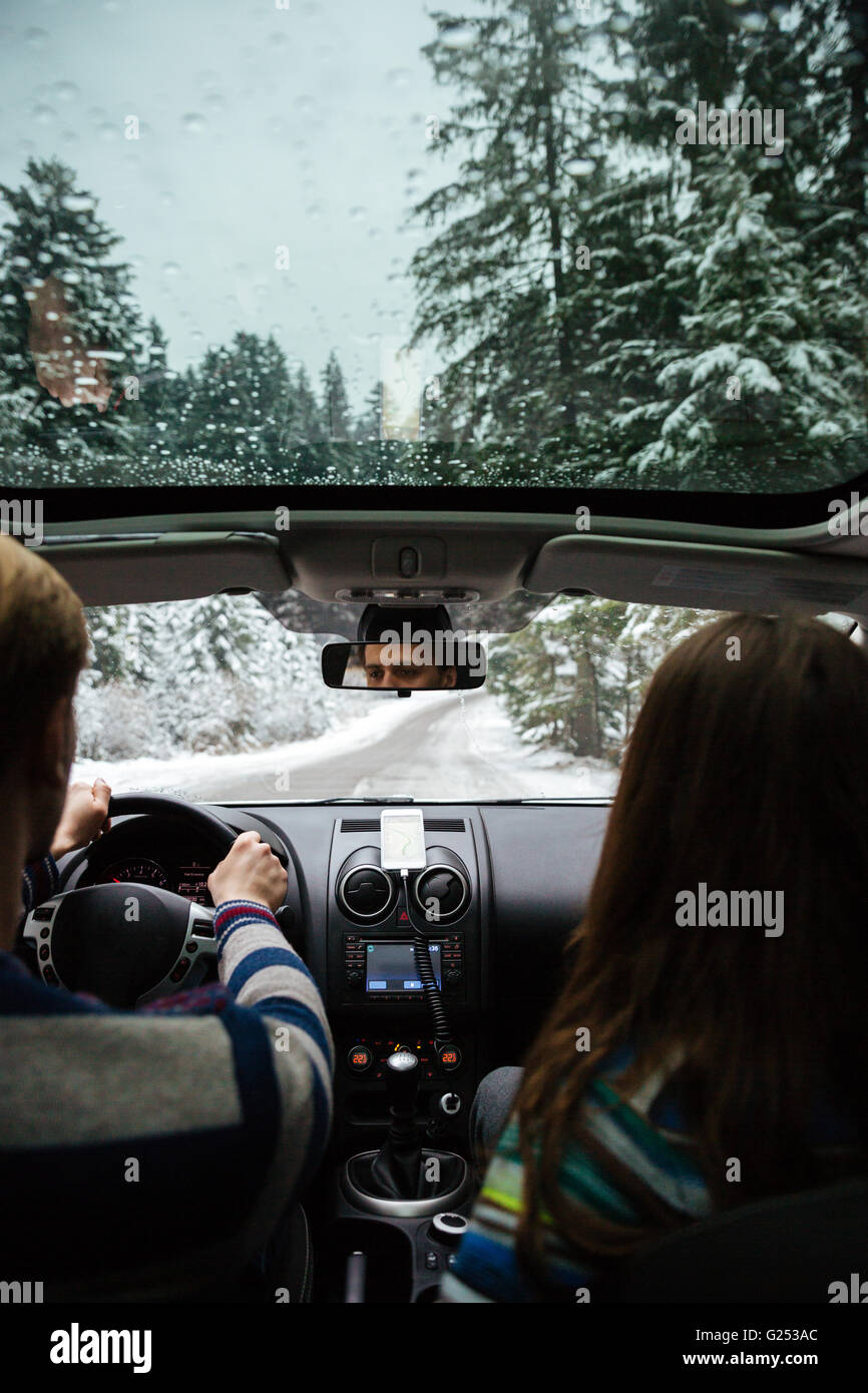 Back view of beautiful young couple driving in modern car with glass ...