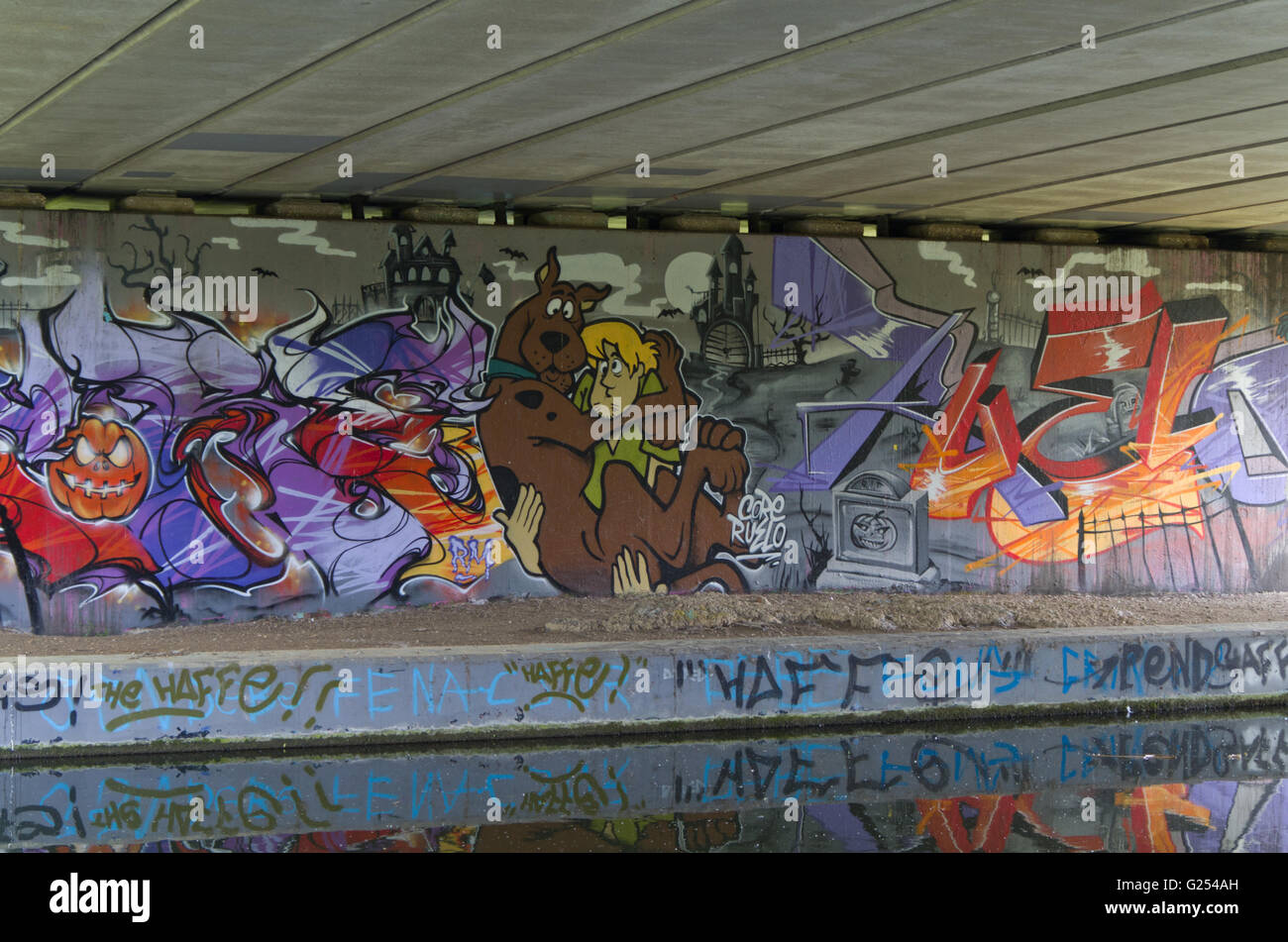 Colourful graffiti under a road bridge over the Grand Union canal ...