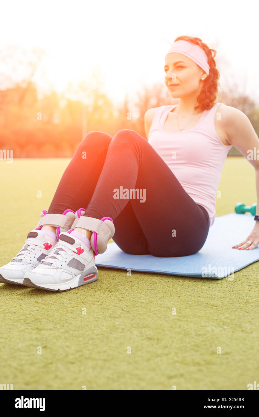 Young slim woman doing exercises on fitness mat outdoors. Beautiful ...