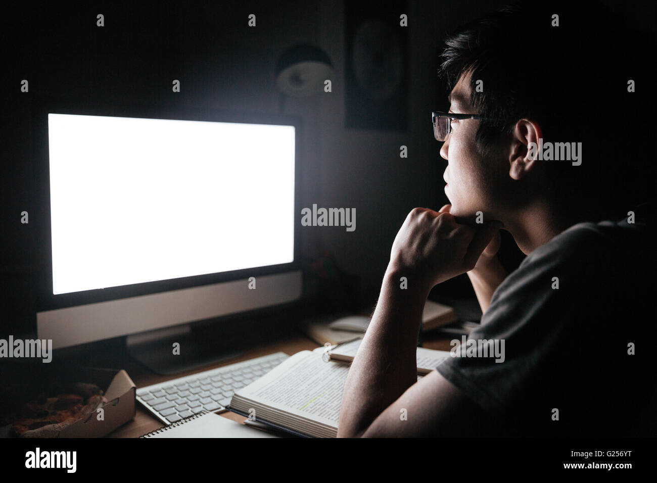 Thoughtful young man in glasses studying using blank screen computer in ... Thoughtful young man in glasses studying using blank screen computer in ...