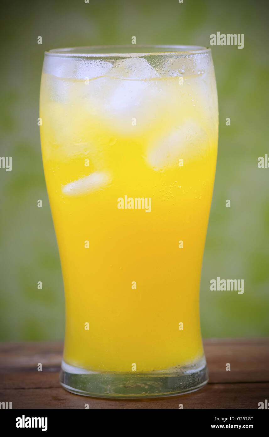 Glass of cold orange drink and ice cubes on wooden table Stock Photo ...