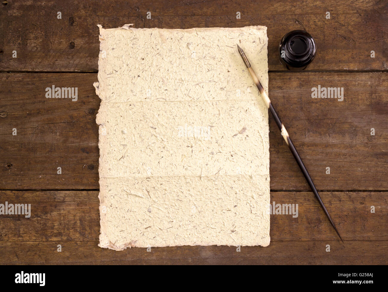 Yellow hand made paper with quill pen and ink on rustic wood table ...