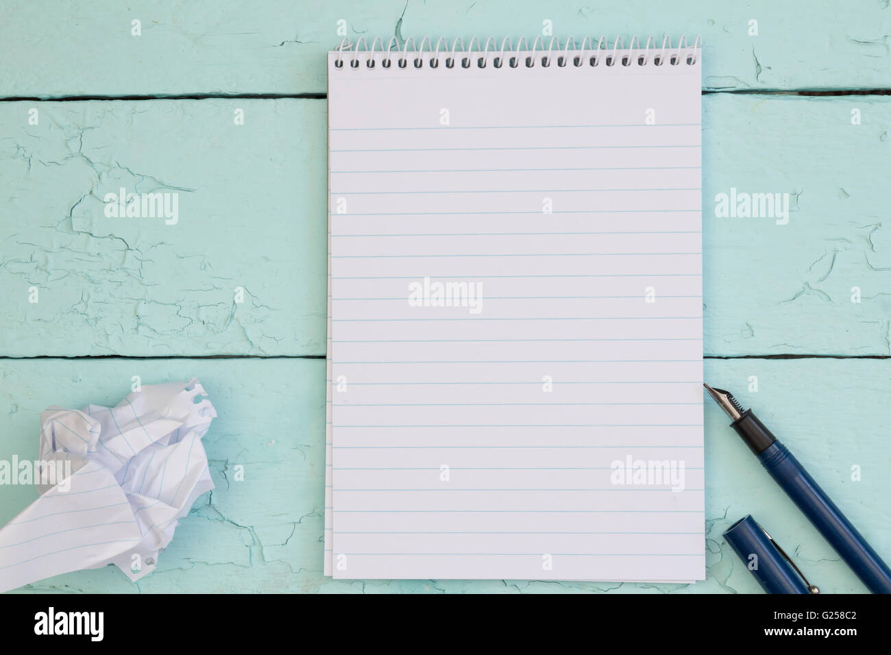 Fountain pen and blank paper note pad on turquoise rustic wood table ...