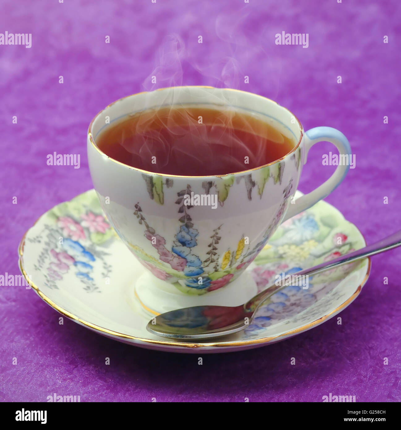 Decorated tea cup with smoke on purple background Stock Photo - Alamy