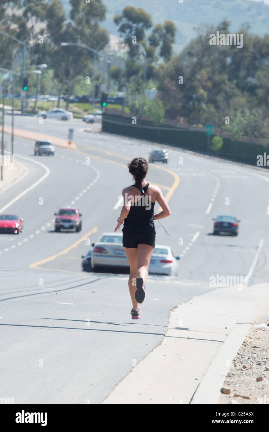 Woman jogging down road Stock Photo - Alamy