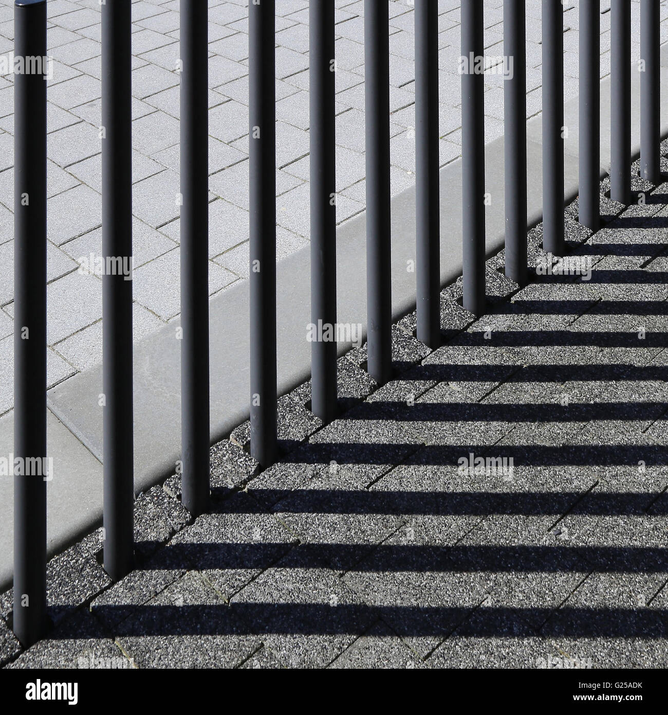Railings and shadows on pavement Stock Photo - Alamy