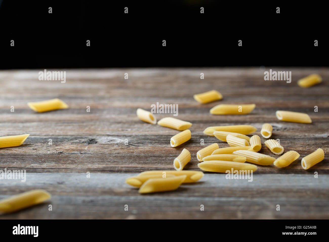 Falling penne pasta. Flying yellow raw macaroni over black background ...