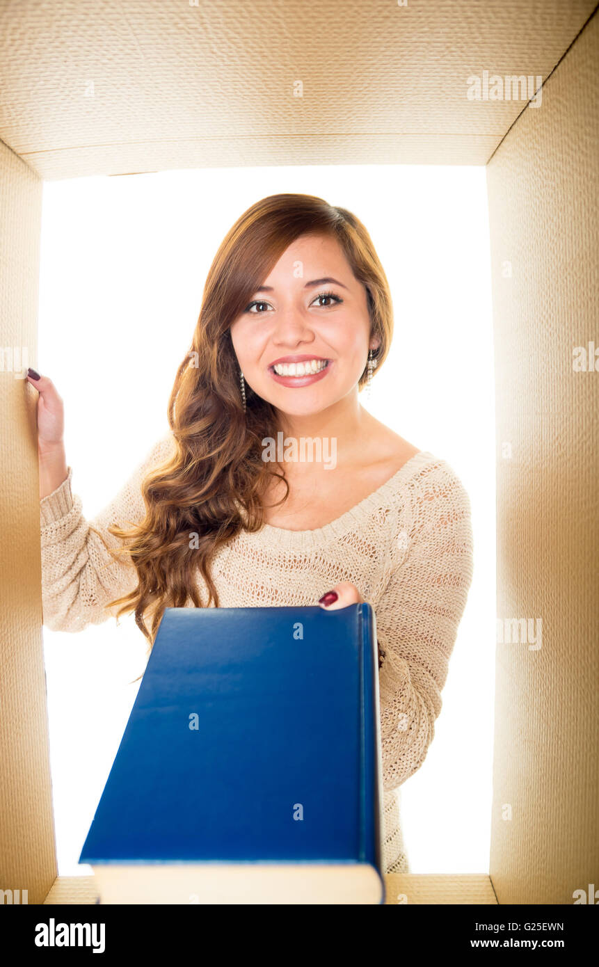 Smiling girl inside the box holding a blue book with one hand and the ...