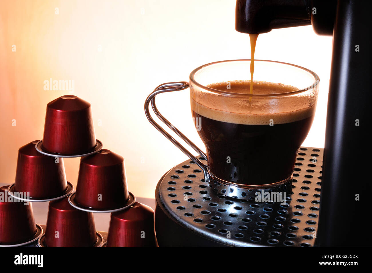 machine serving espresso coffee in a glass cup and stack of capsules ...