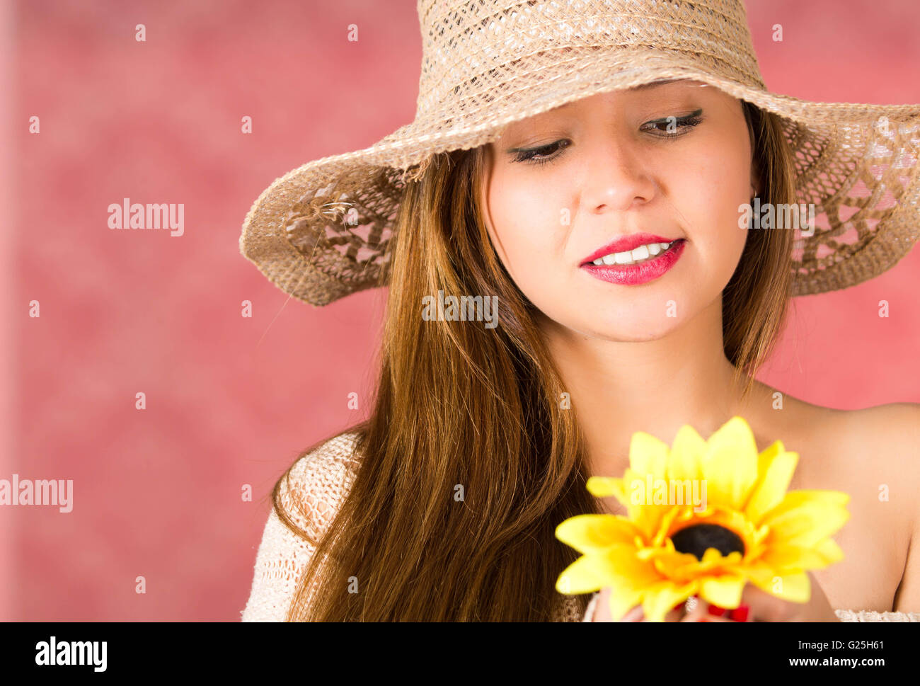 Woman serious and pensative mood looking a sunflower. Hat in beige ...
