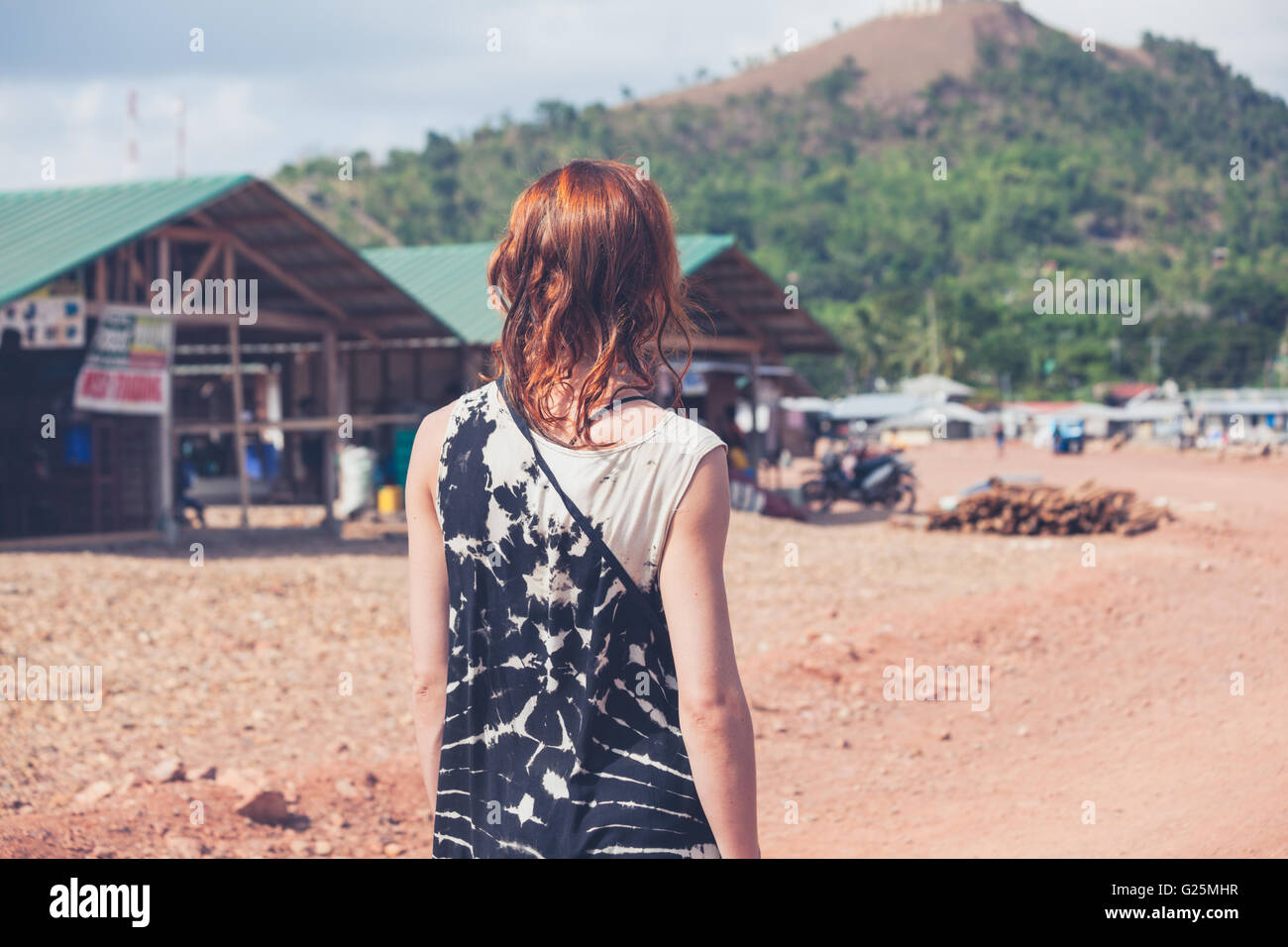 A young caucasian woman is walking around a small town in a developing ...