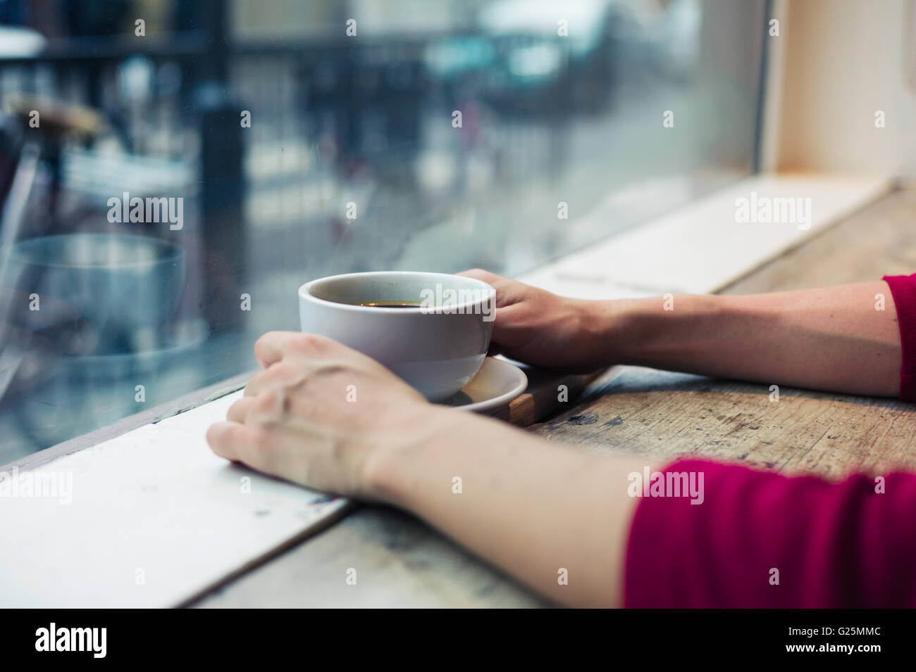 A young woman is having a coffee by the window in a cafe Stock Photo ...