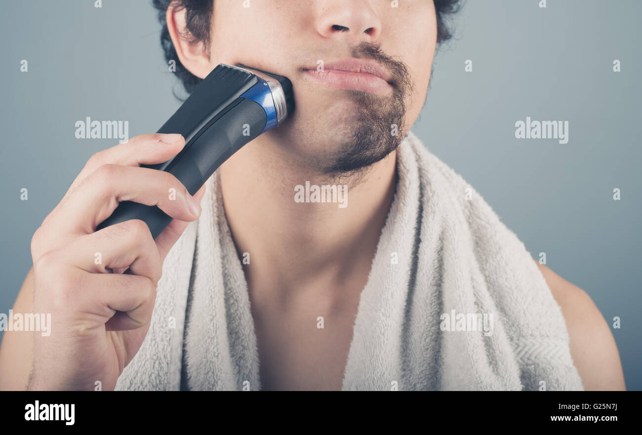 A young man is shaving off half of his beard Stock Photo - Alamy