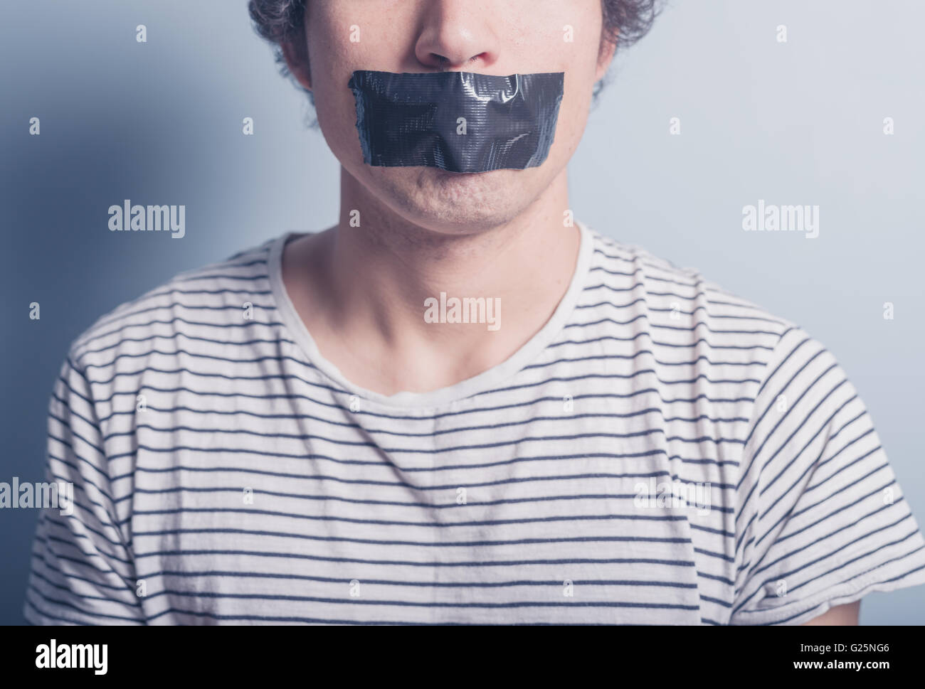 A young man has a big piece of black industrial tape covering his mouth Stock Photo - Alamy