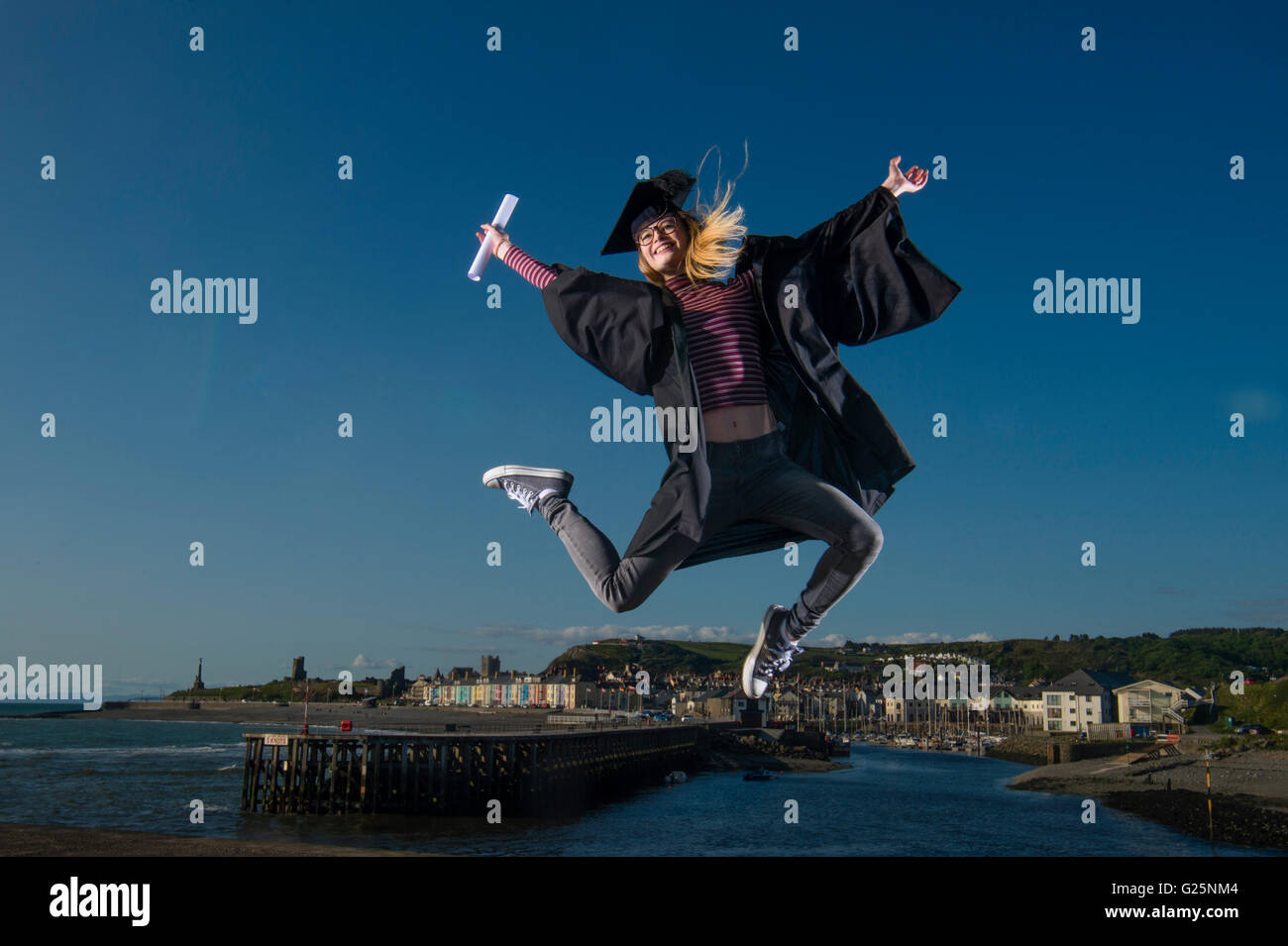 Jumping for joy: A happy young woman girl student wearing a university ...