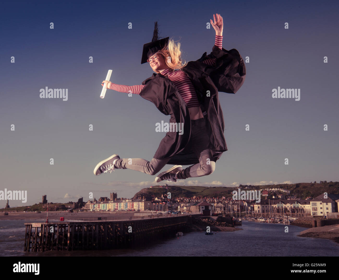 Jumping for joy: A happy young woman girl student wearing a university ...