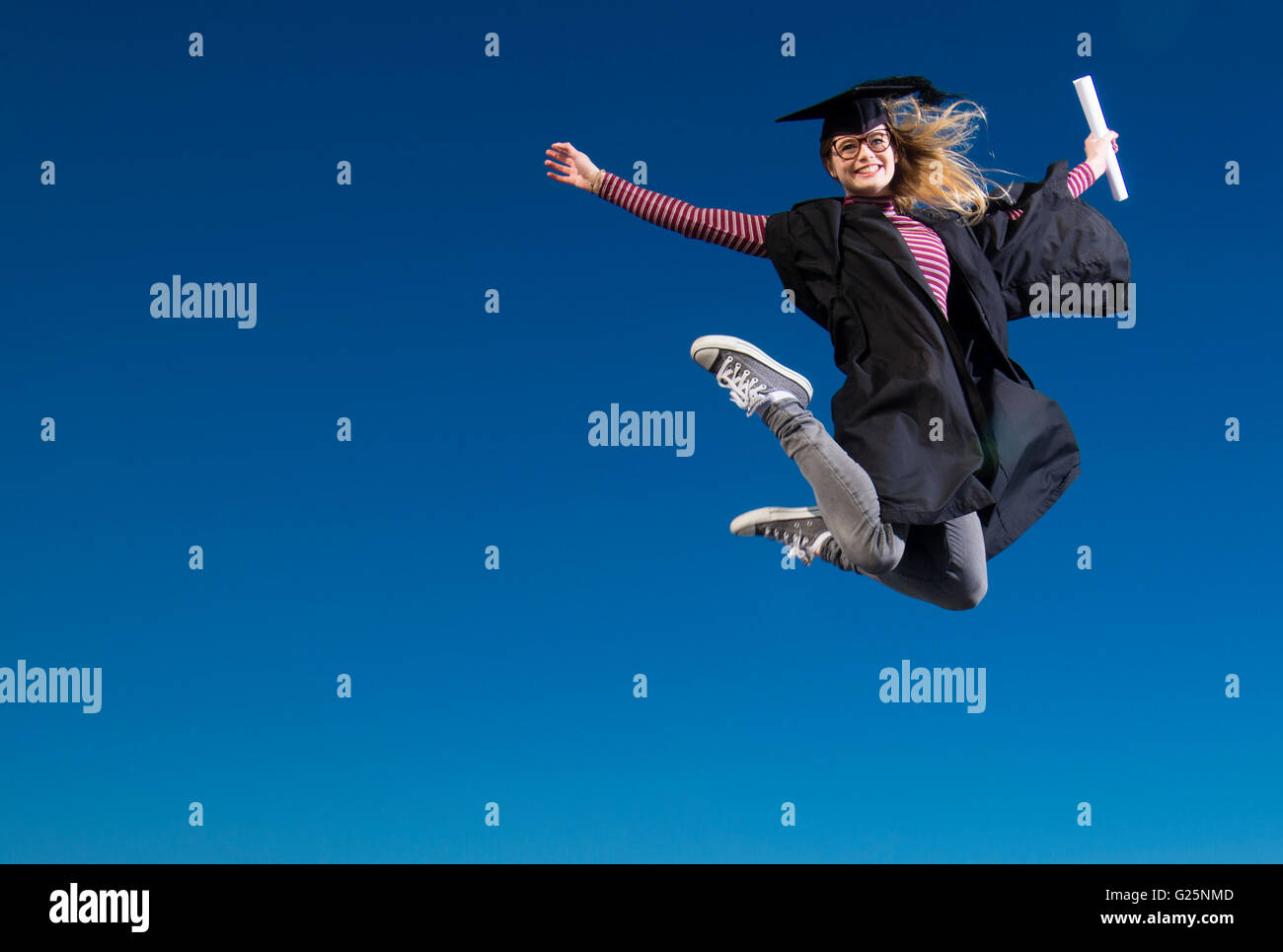 Jumping for joy: A happy young woman girl student wearing a university ...