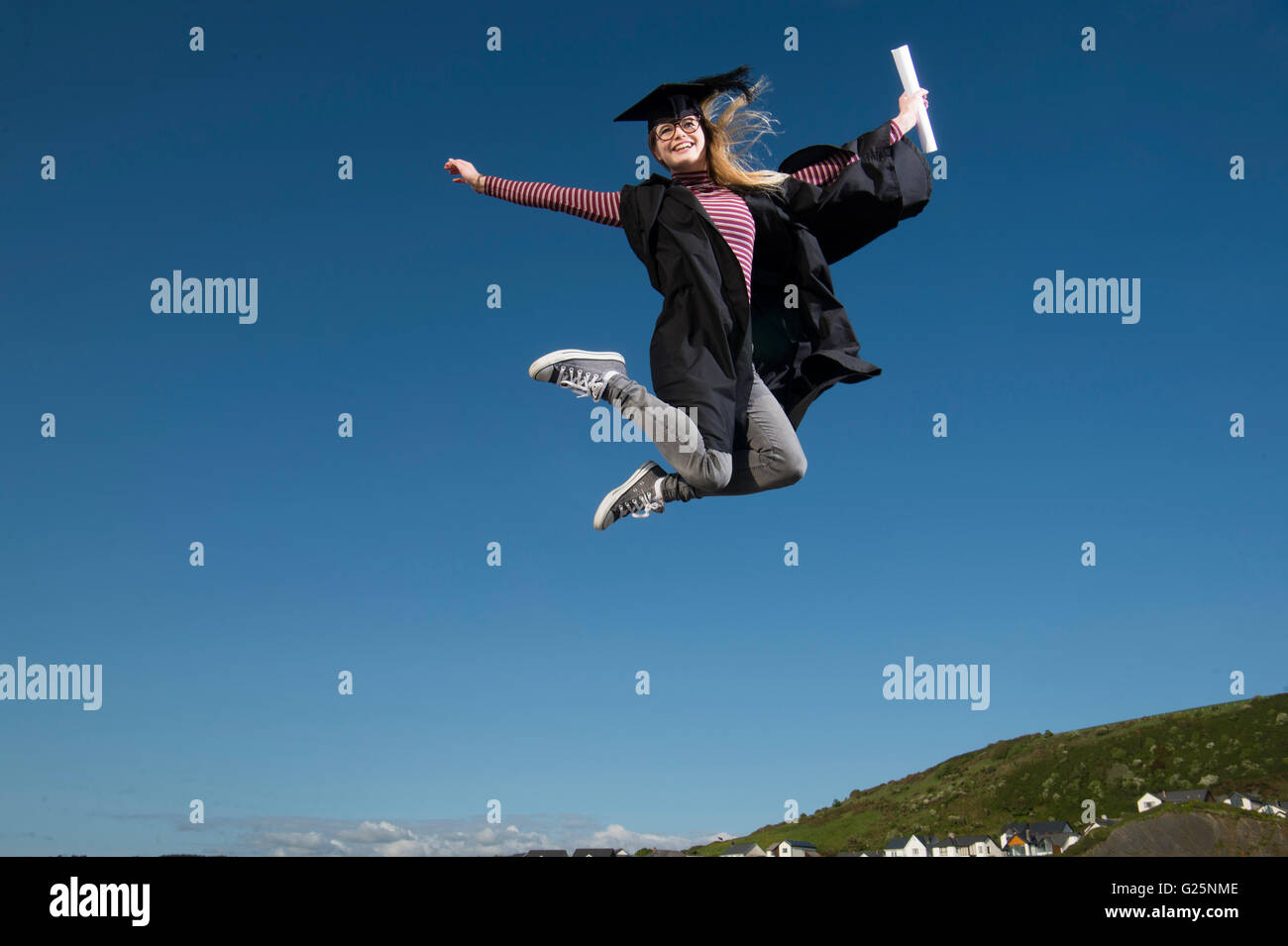Jumping for joy: A happy young woman girl student wearing a university ...