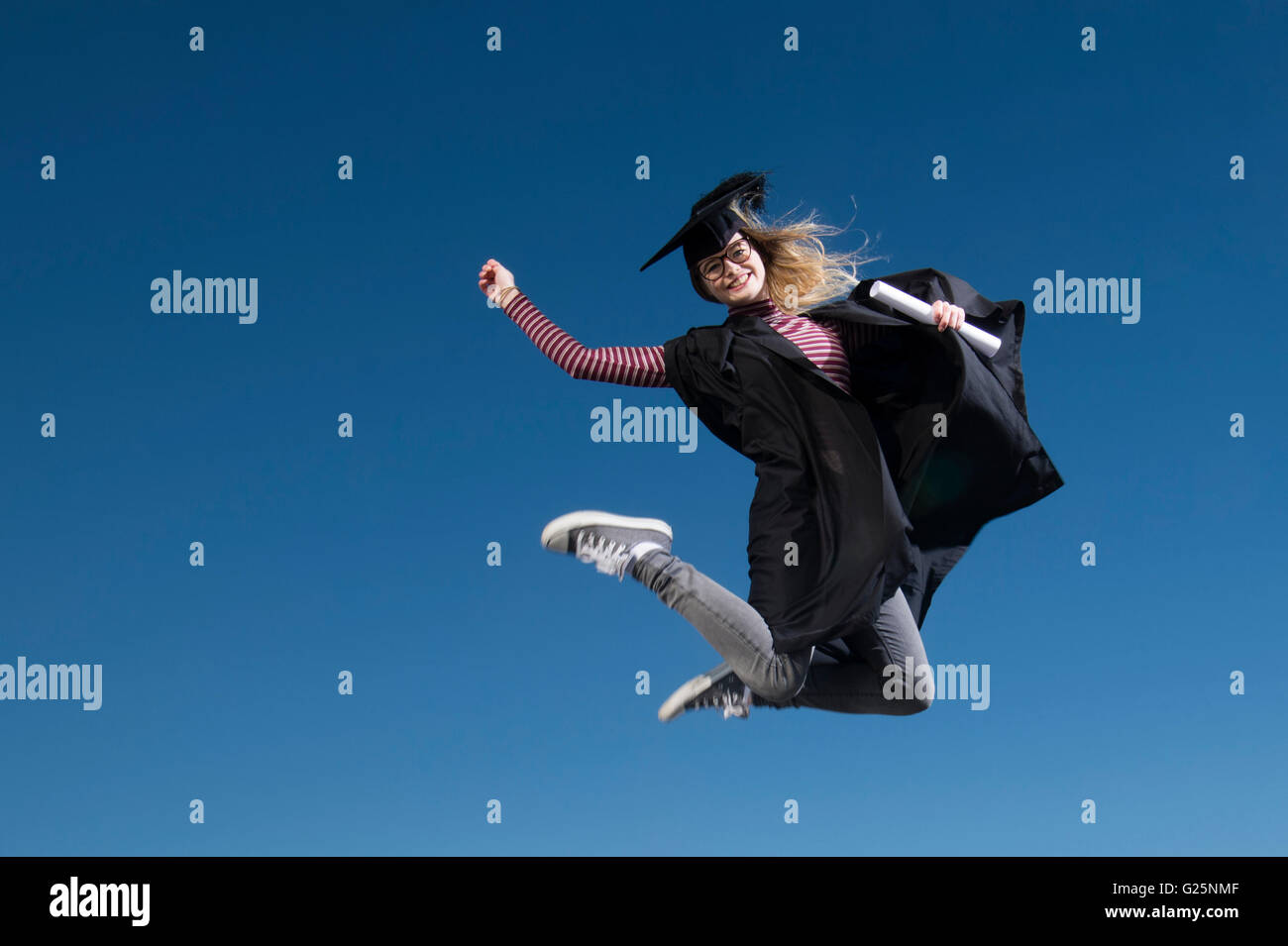 Jumping for joy: A happy young woman girl student wearing a university ...