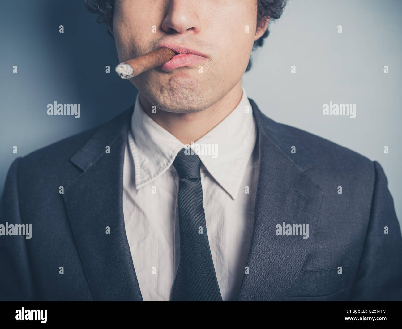 A young confident businessman is smoking a cigar Stock Photo - Alamy