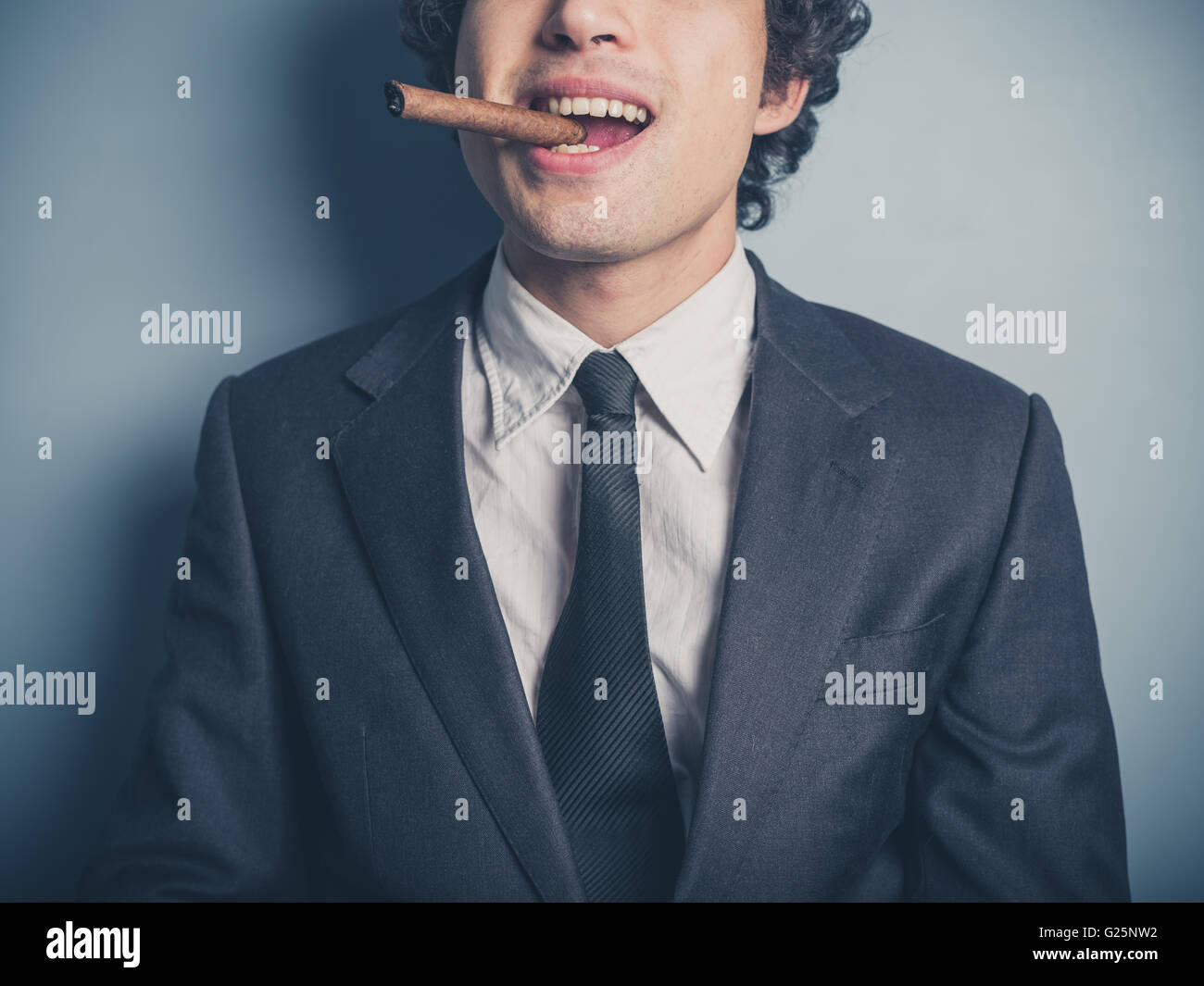 A young confident businessman is smoking a cigar Stock Photo - Alamy