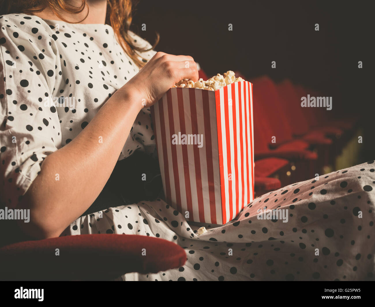 Closeup on a young woman eating popcorn in a movie theater Stock Photo ...